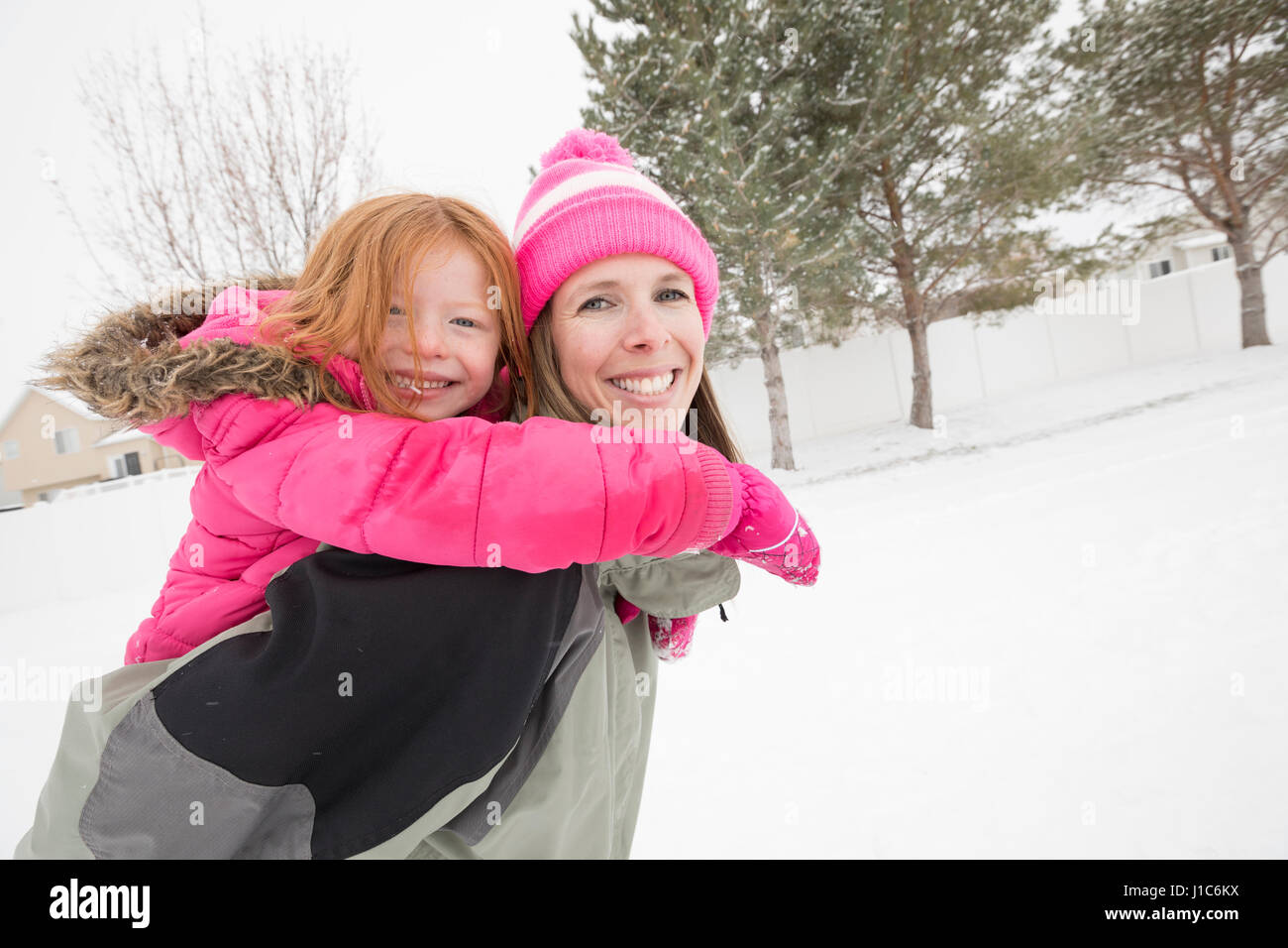 Smiling mother carrying daughter piggyback in winter Stock Photo - Alamy