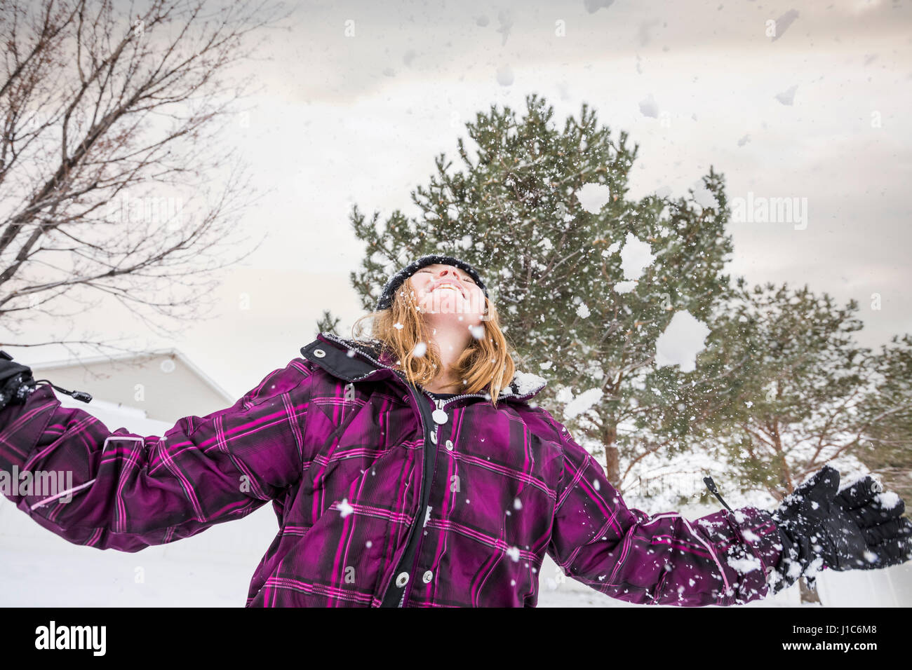 Smiling girl throwing snow in air Stock Photo - Alamy