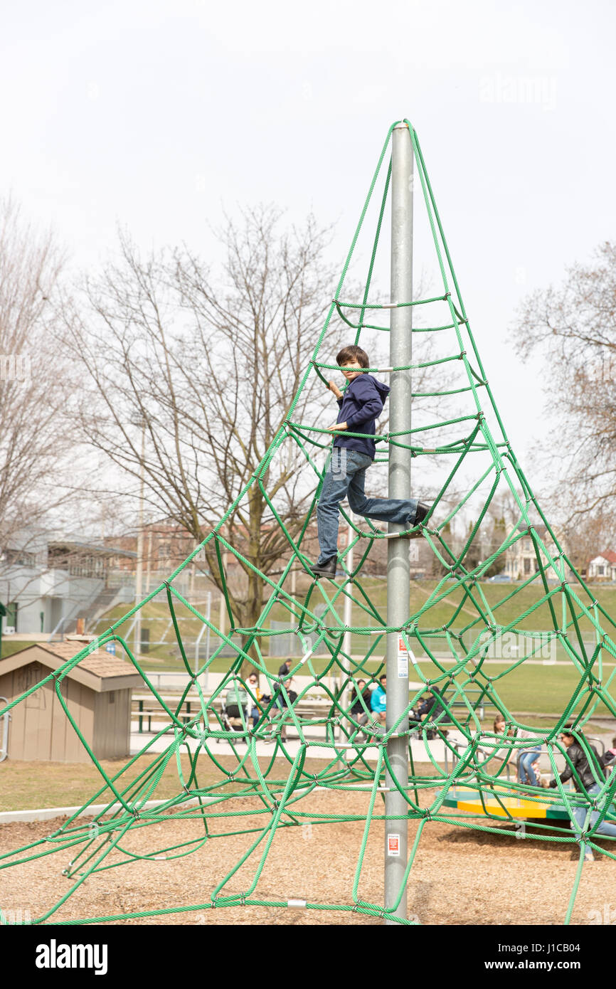 TEN YEAR OLD BOY CLIMBS GIANT ROPE STRUCTURE ON WARM SPRING DAY AT ...