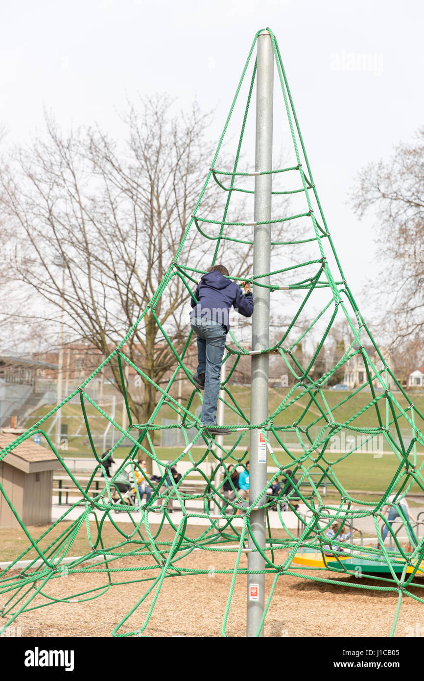 TEN YEAR OLD BOY CLIMBS GIANT ROPE STRUCTURE ON WARM SPRING DAY AT ...