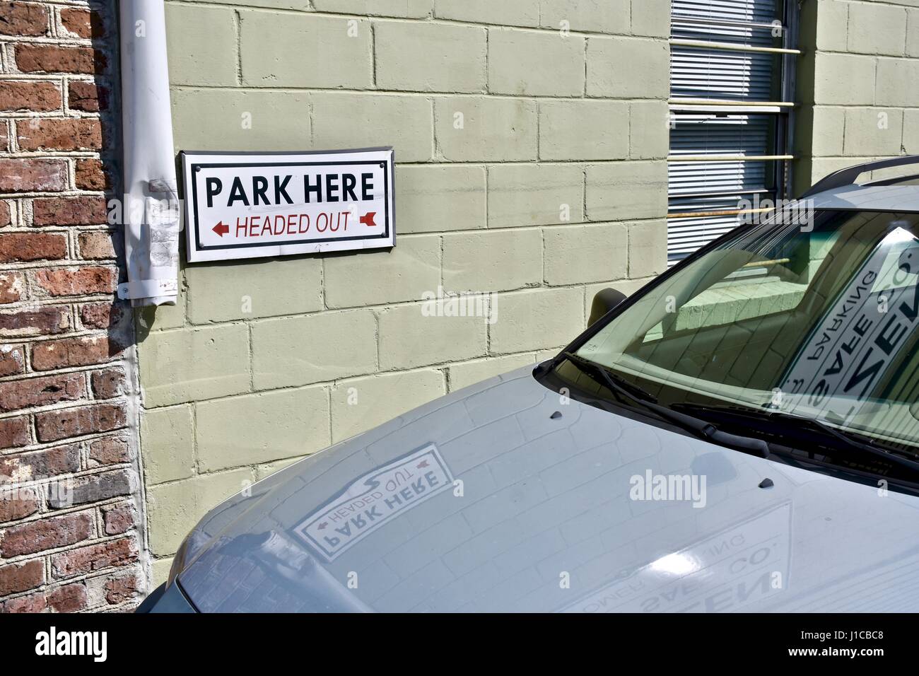 Park here headed out sign with car parked Stock Photo - Alamy