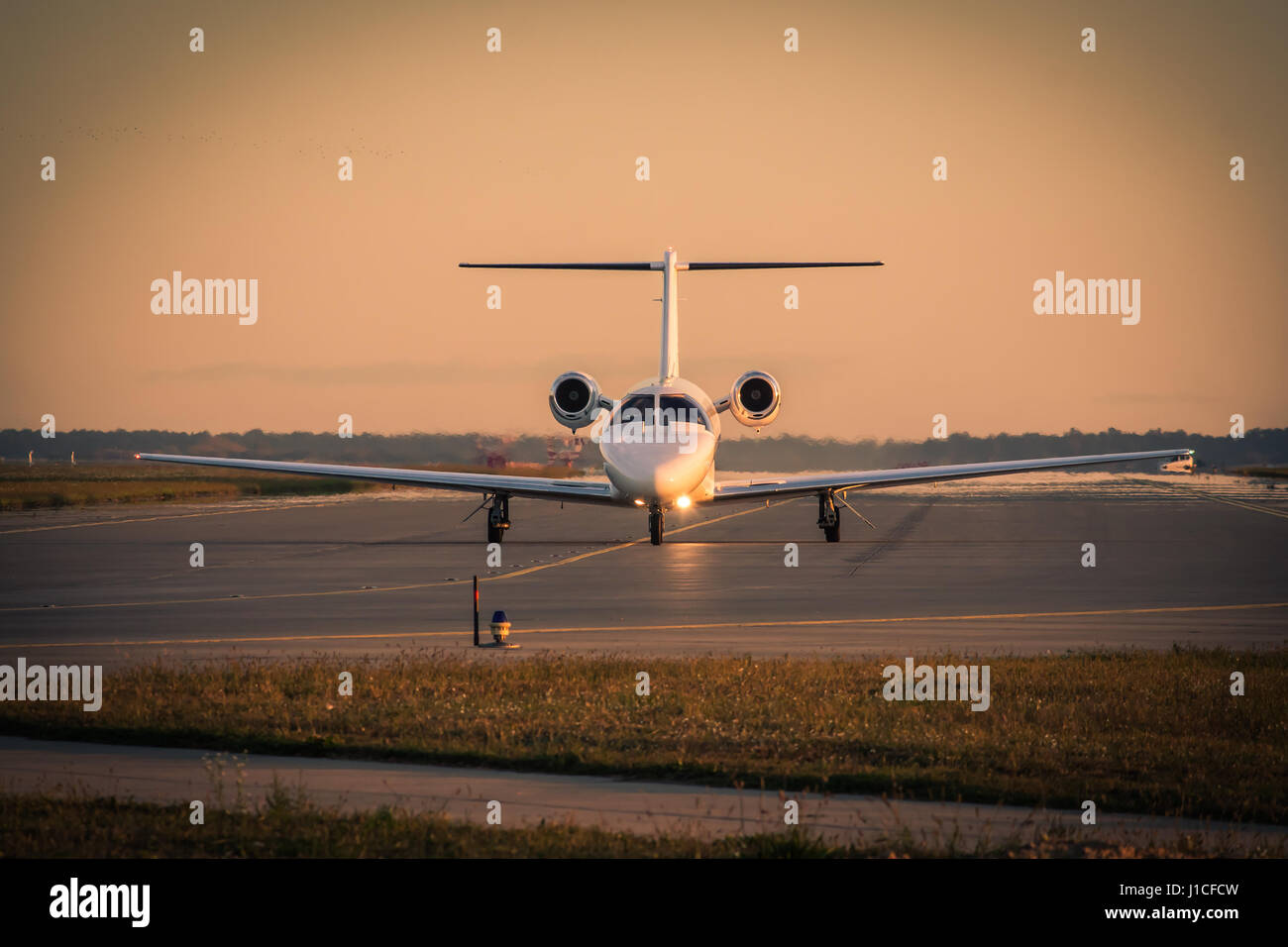 Business jet taxiing along the runway on sunset in the airport Stock ...
