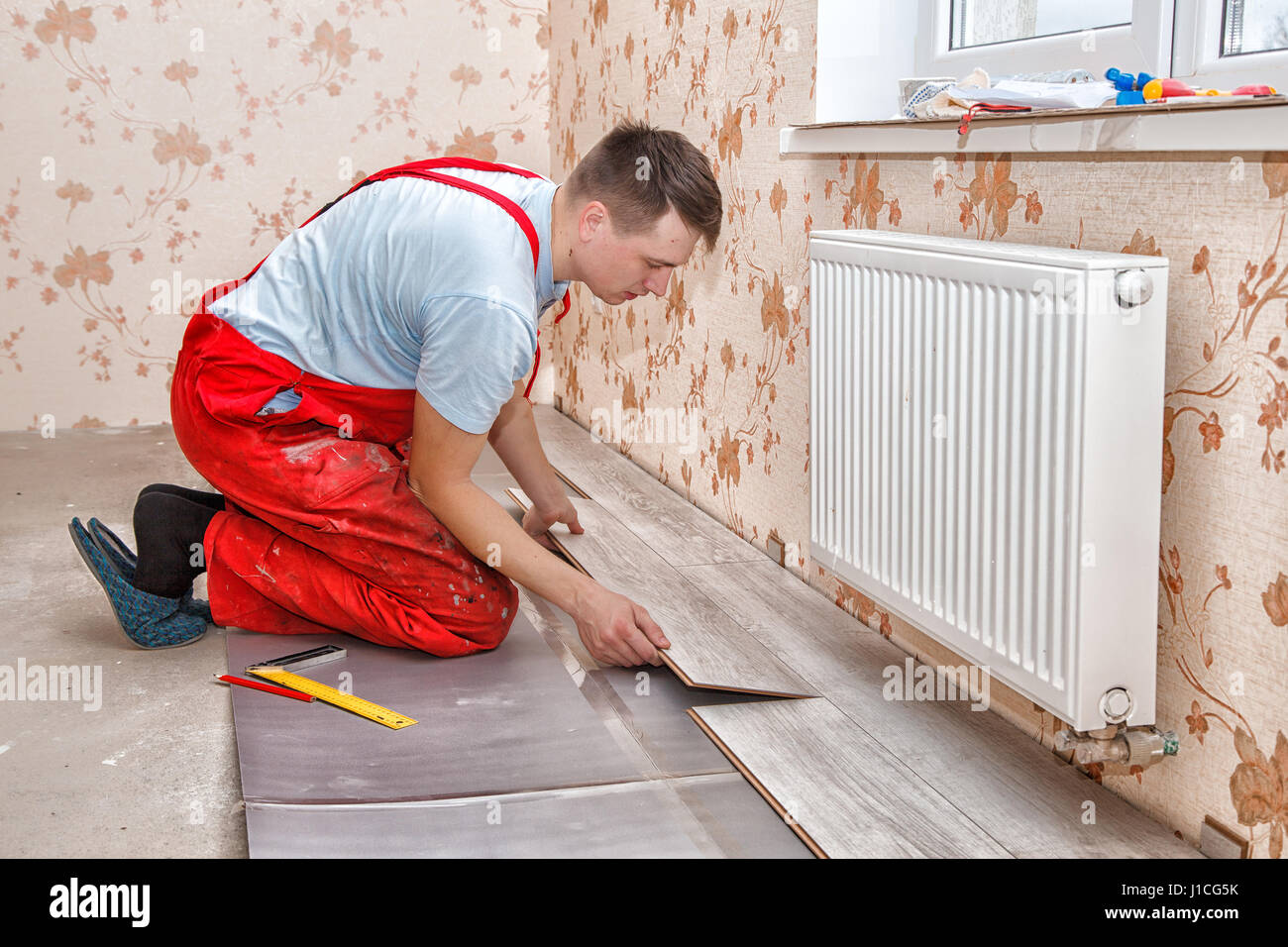 young handyman installing wooden floor in new house Stock Photo - Alamy
