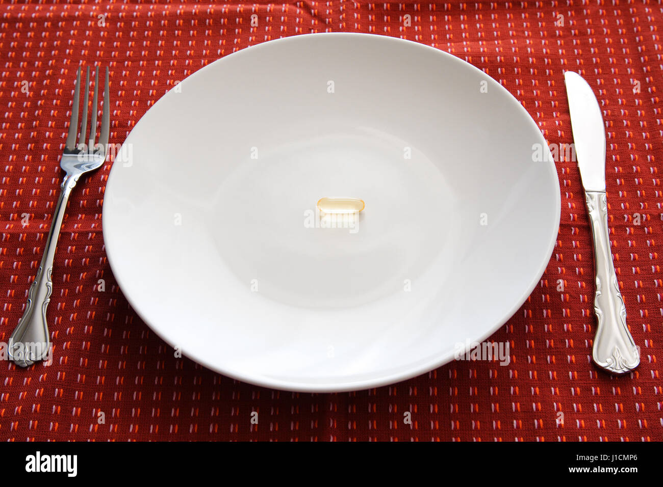 A shot of a single medicine pill on a plate with fork and knife Stock ...