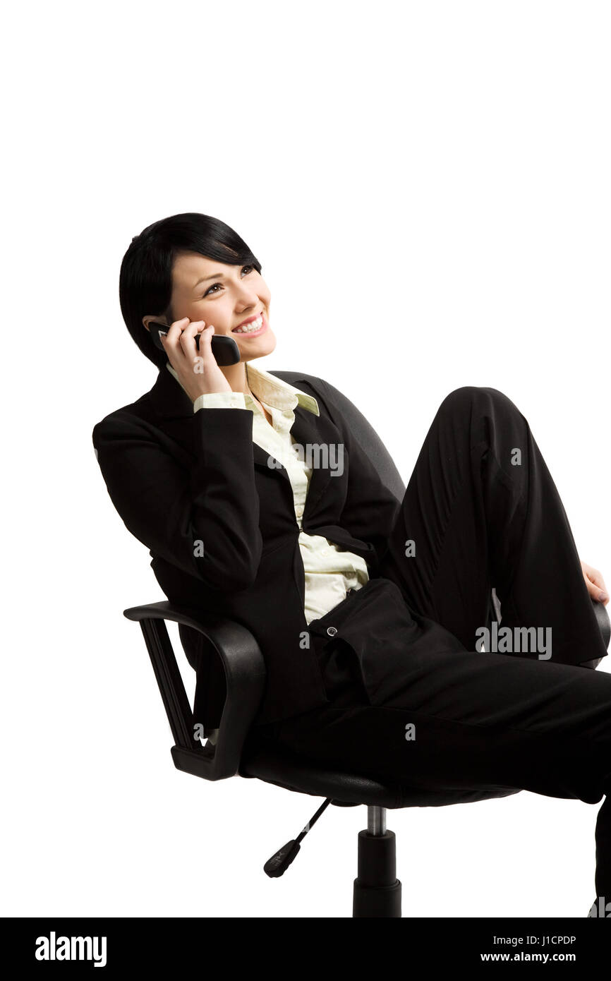 An isolated shot of a businesswoman sitting on a chair and talking on ...