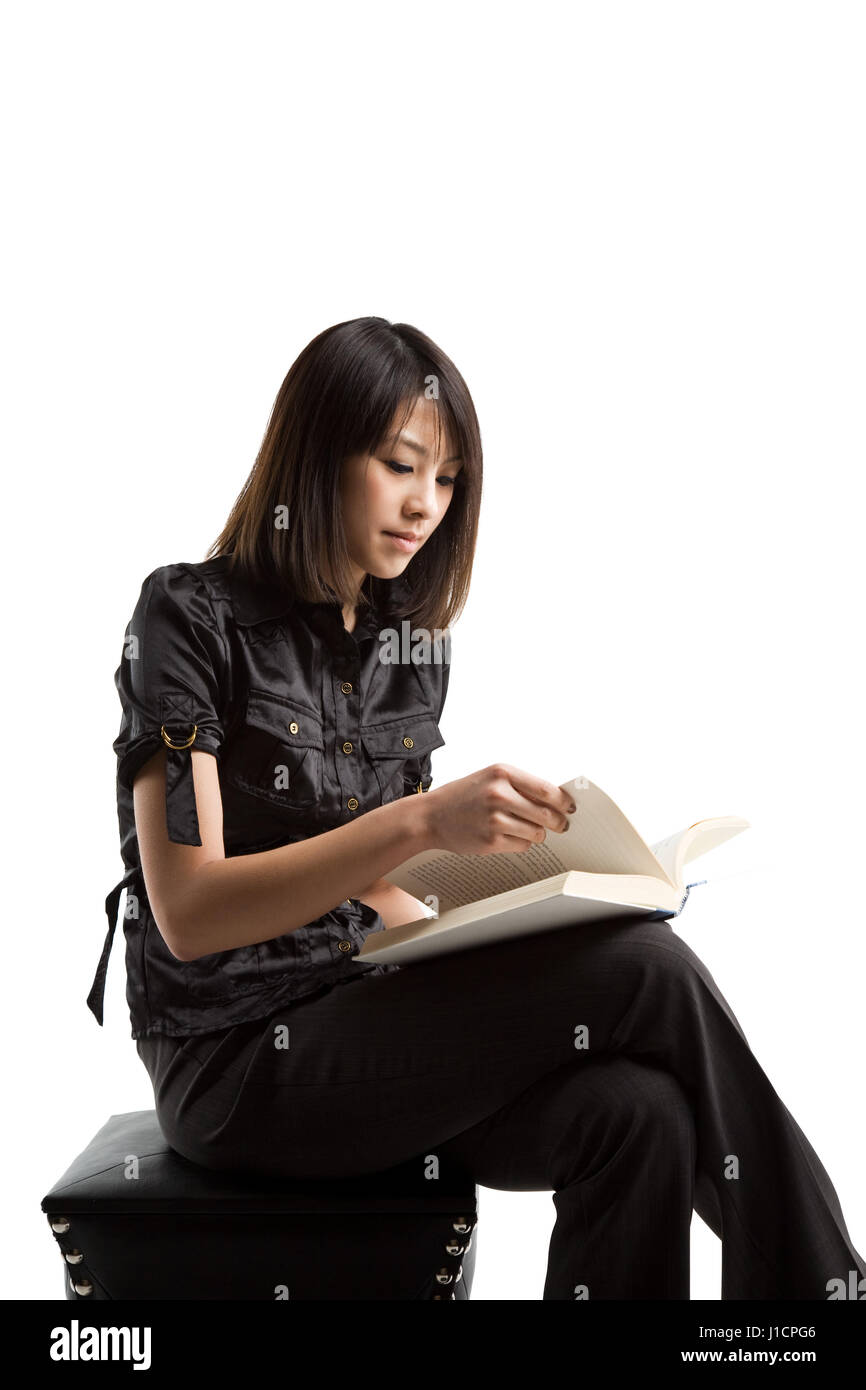 An isolated shot of a beautiful young asian student reading a book ...