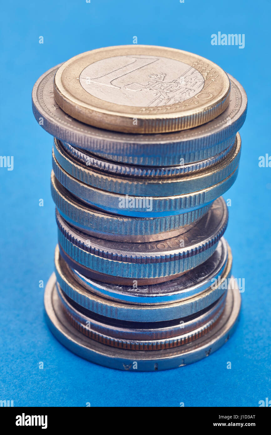 Different kinds of coins over a blue background. Macro detail. Vertical ...