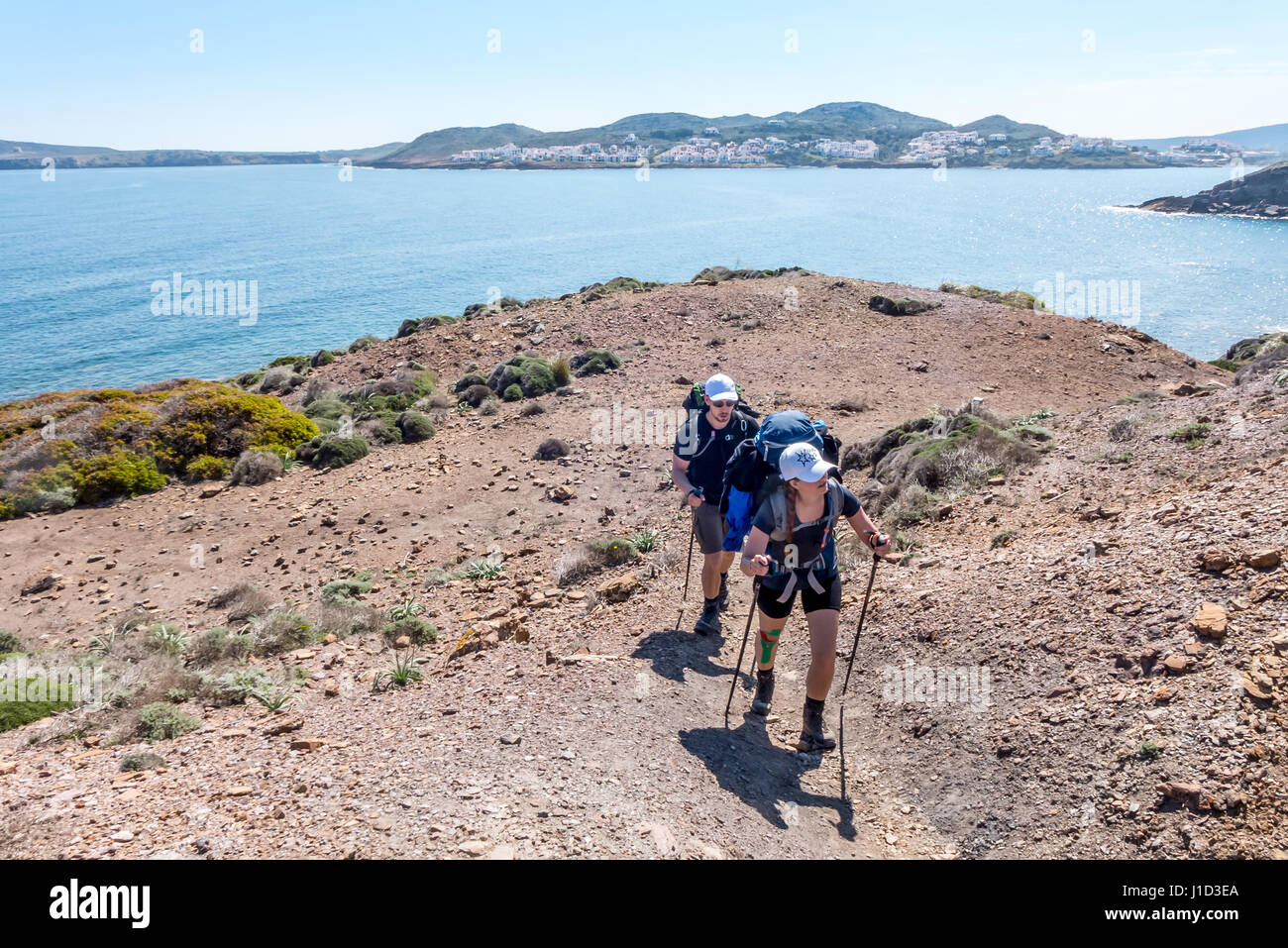 Walkers hiking on the coastal path near Platges de Fornells in Menorca ...