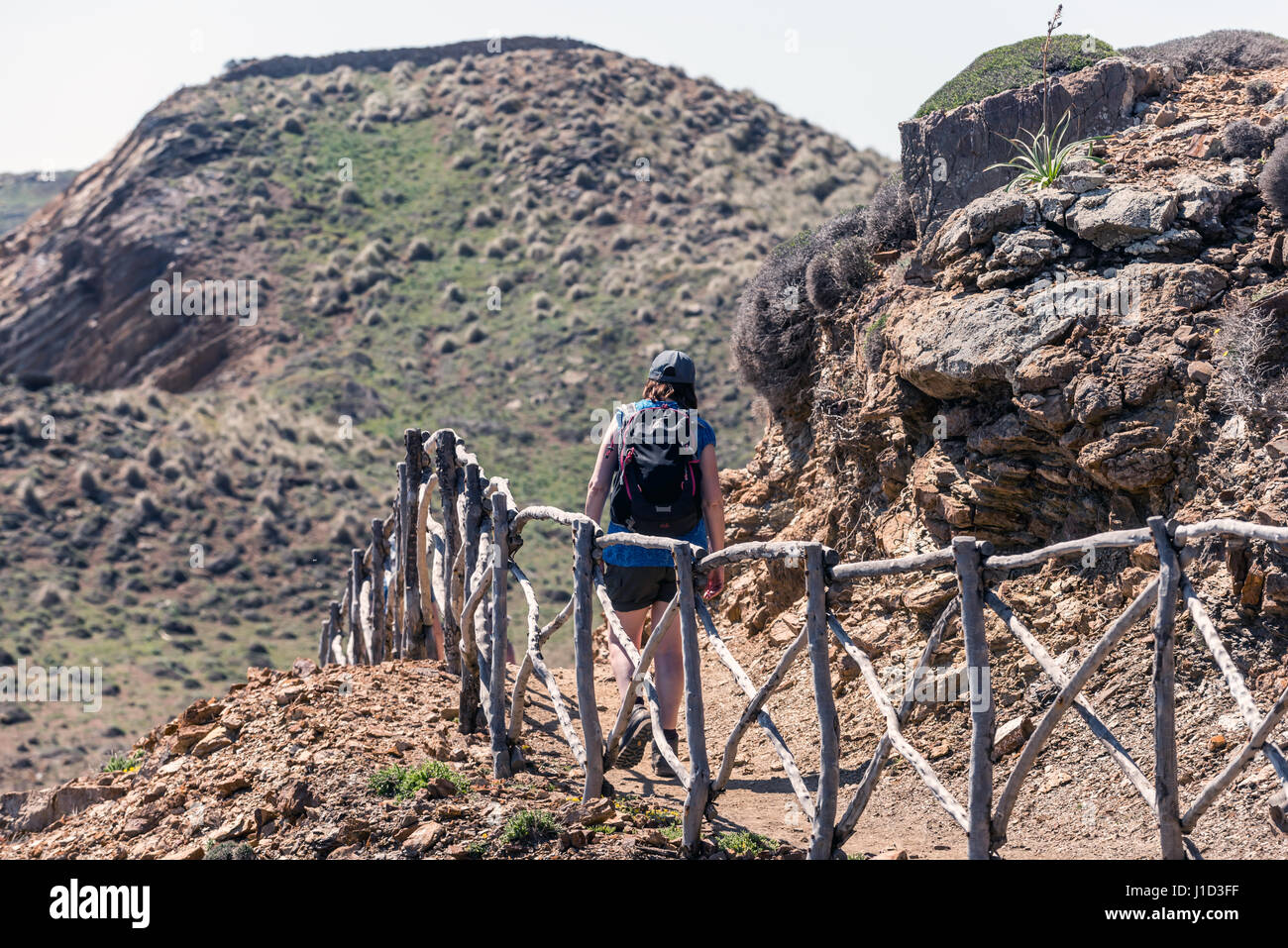 A hiker walking on the coastal path near Platges de Fornells in Menorca ...