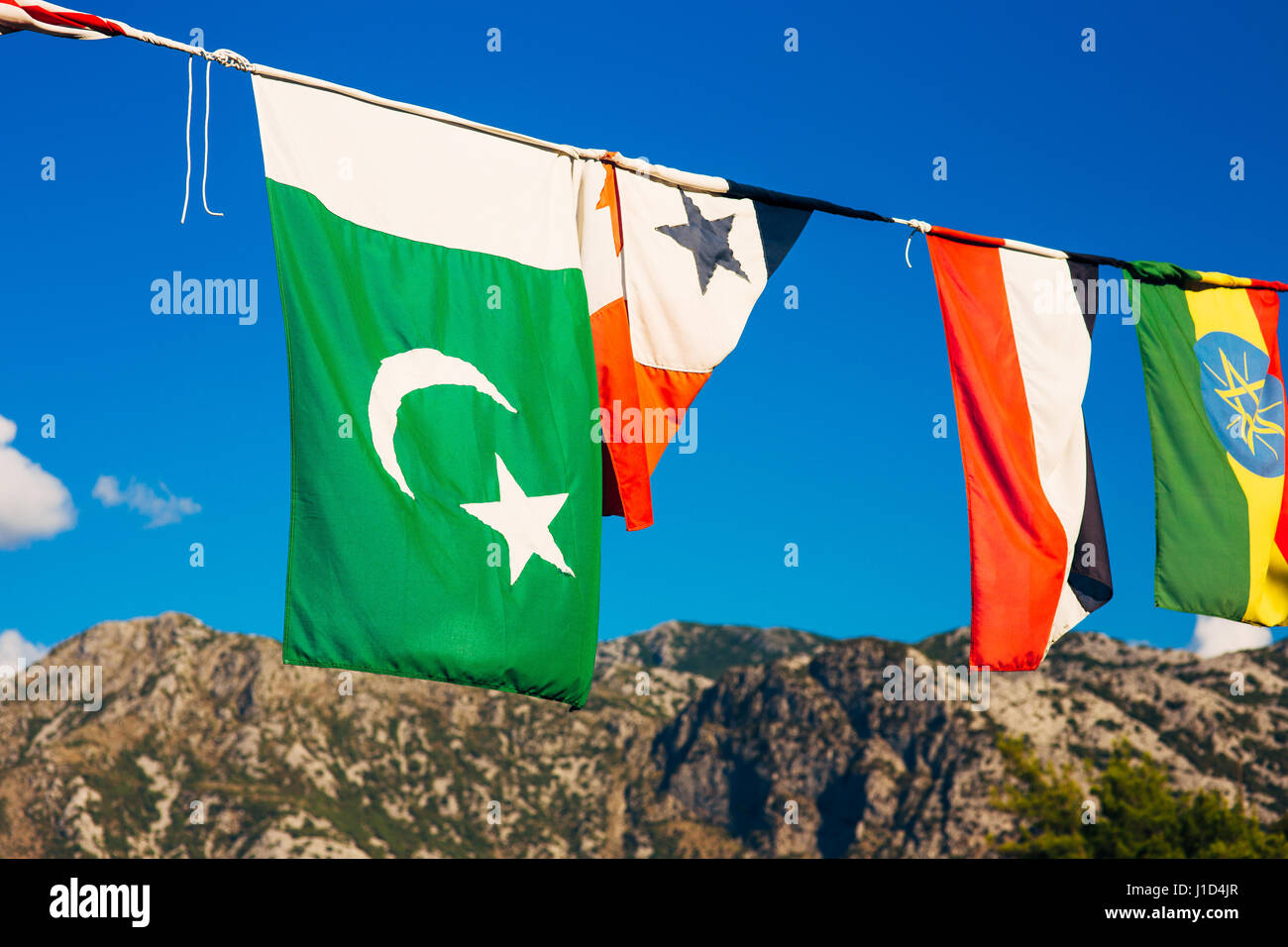 The flag of Pakistan is hanging on a rope with other flags against ...
