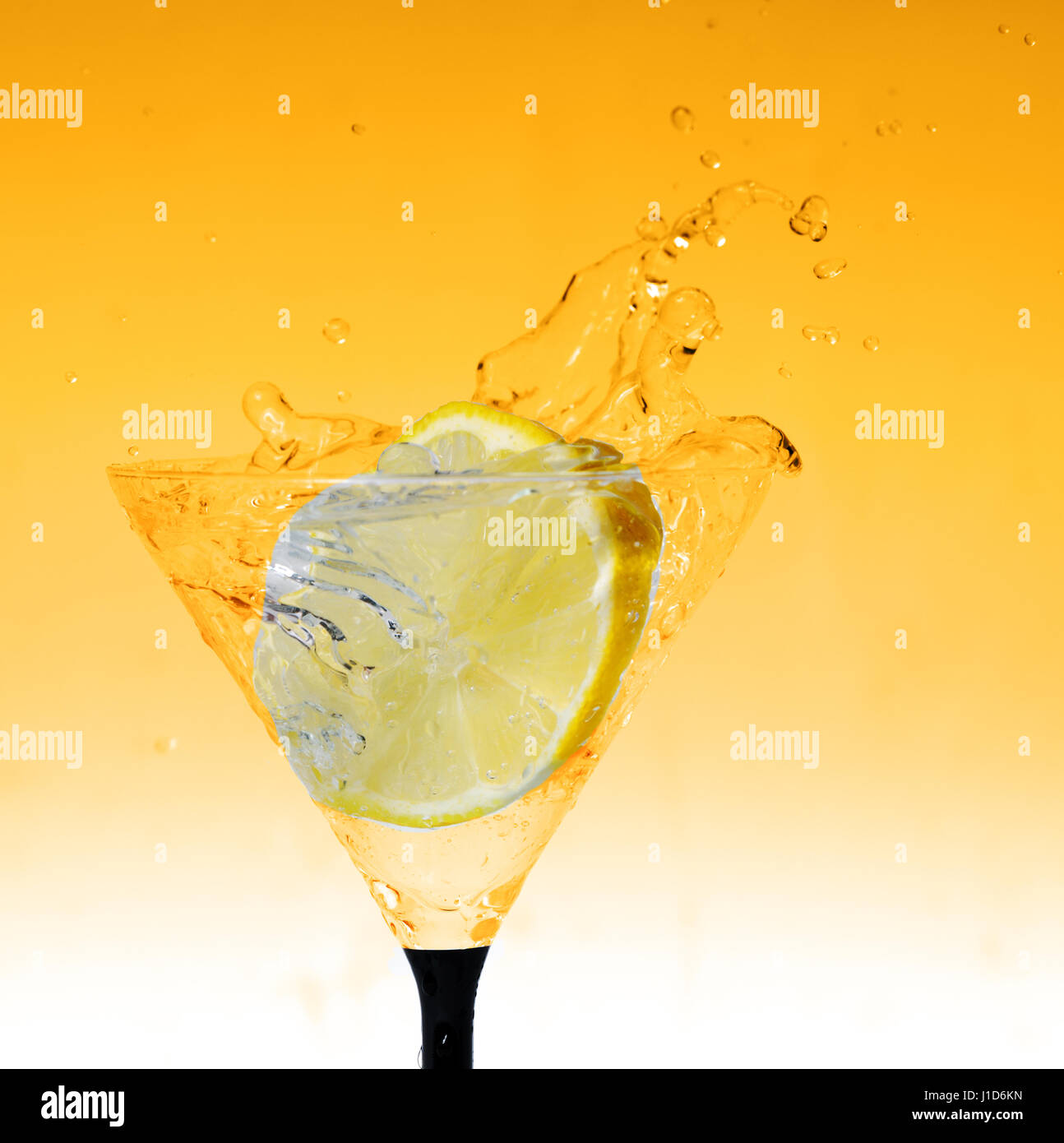fresh lemon in glass with sparkling water splash with yellow background ...