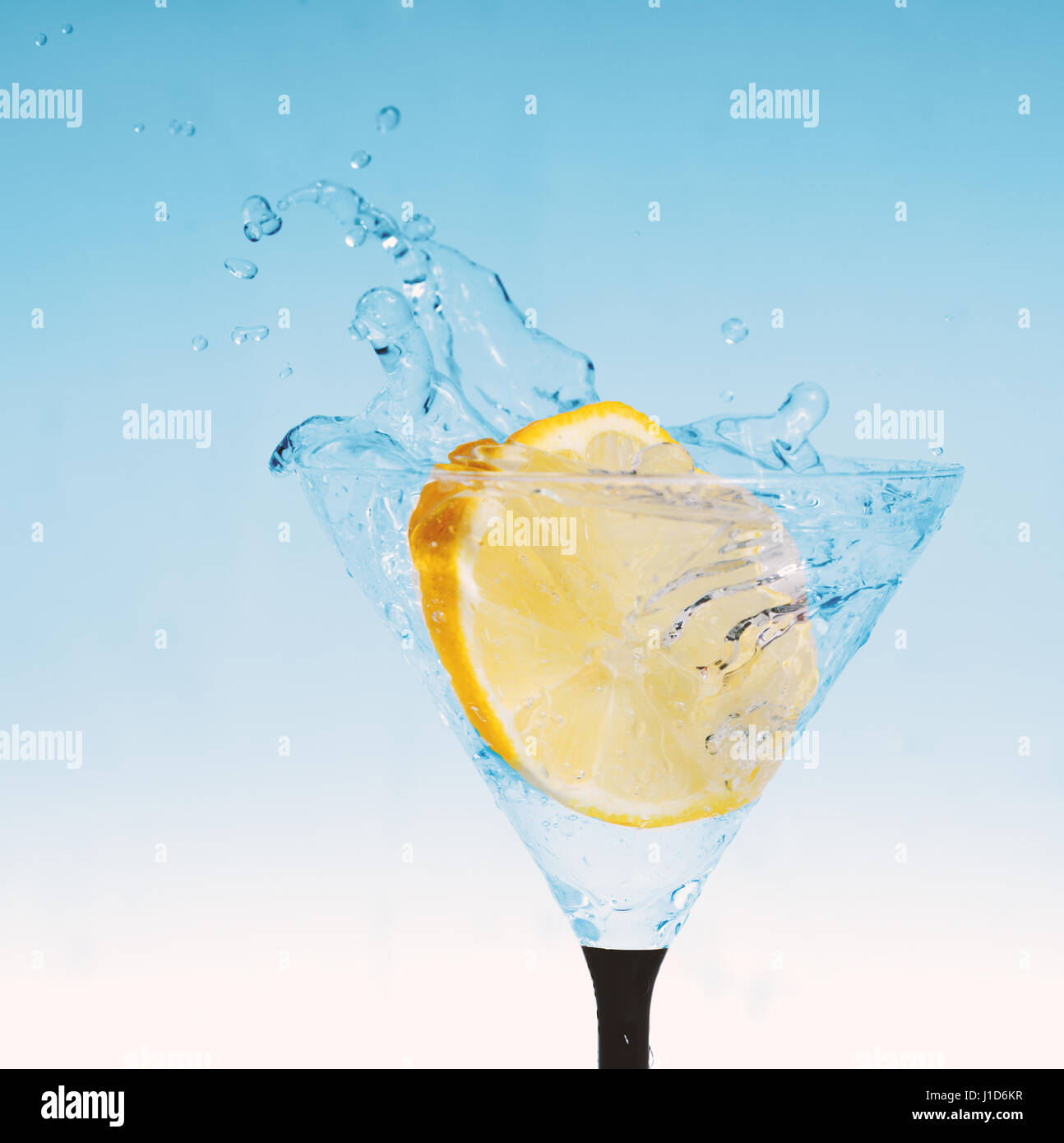 fresh lemon in glass with sparkling water splash with light blue ...