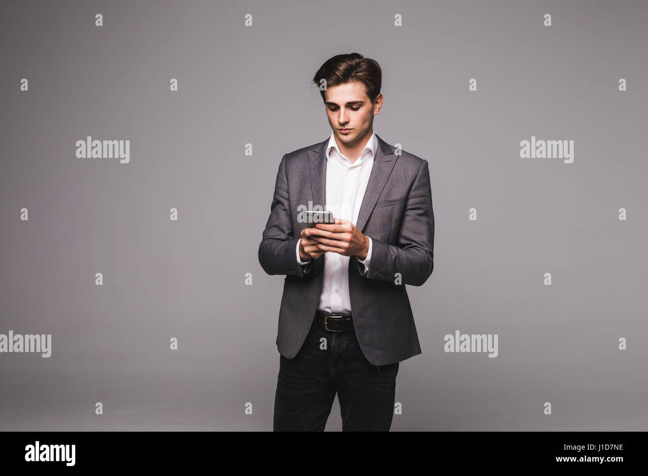 Young business man texting a message with phone over gray background ...