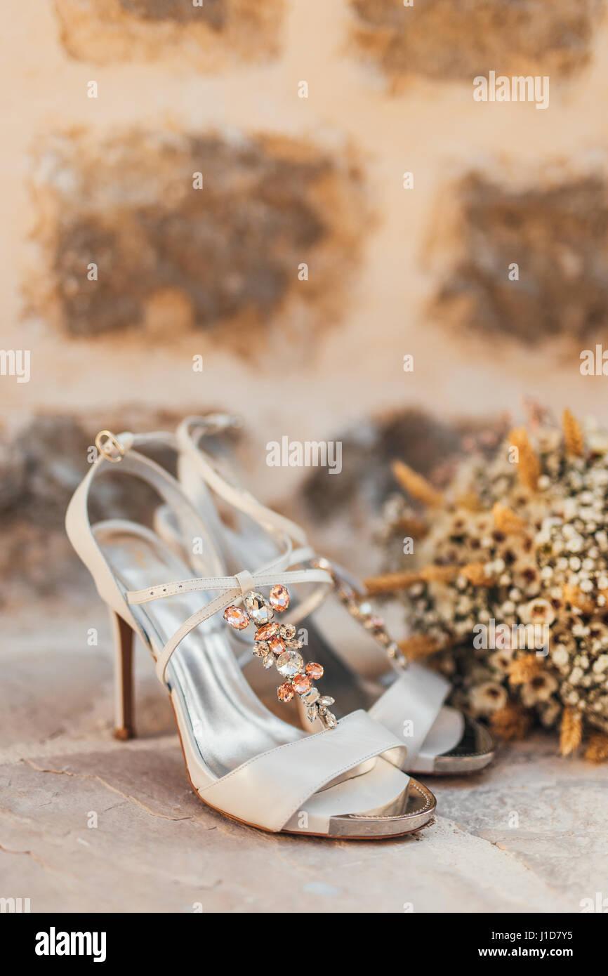 Wedding shoes of a bride on a stone background and a white bridal ...