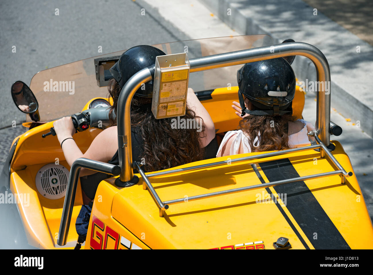 Two young women are driving small car of GoCar tours through town ...