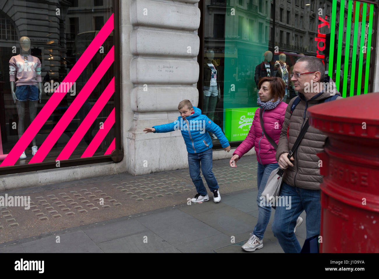 A young boy stretches in the street outside the window of fashion brand ...