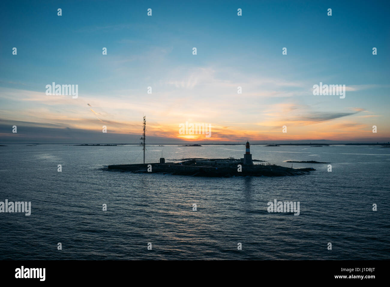 Small island with lighthouse and communication tower against scenic ...