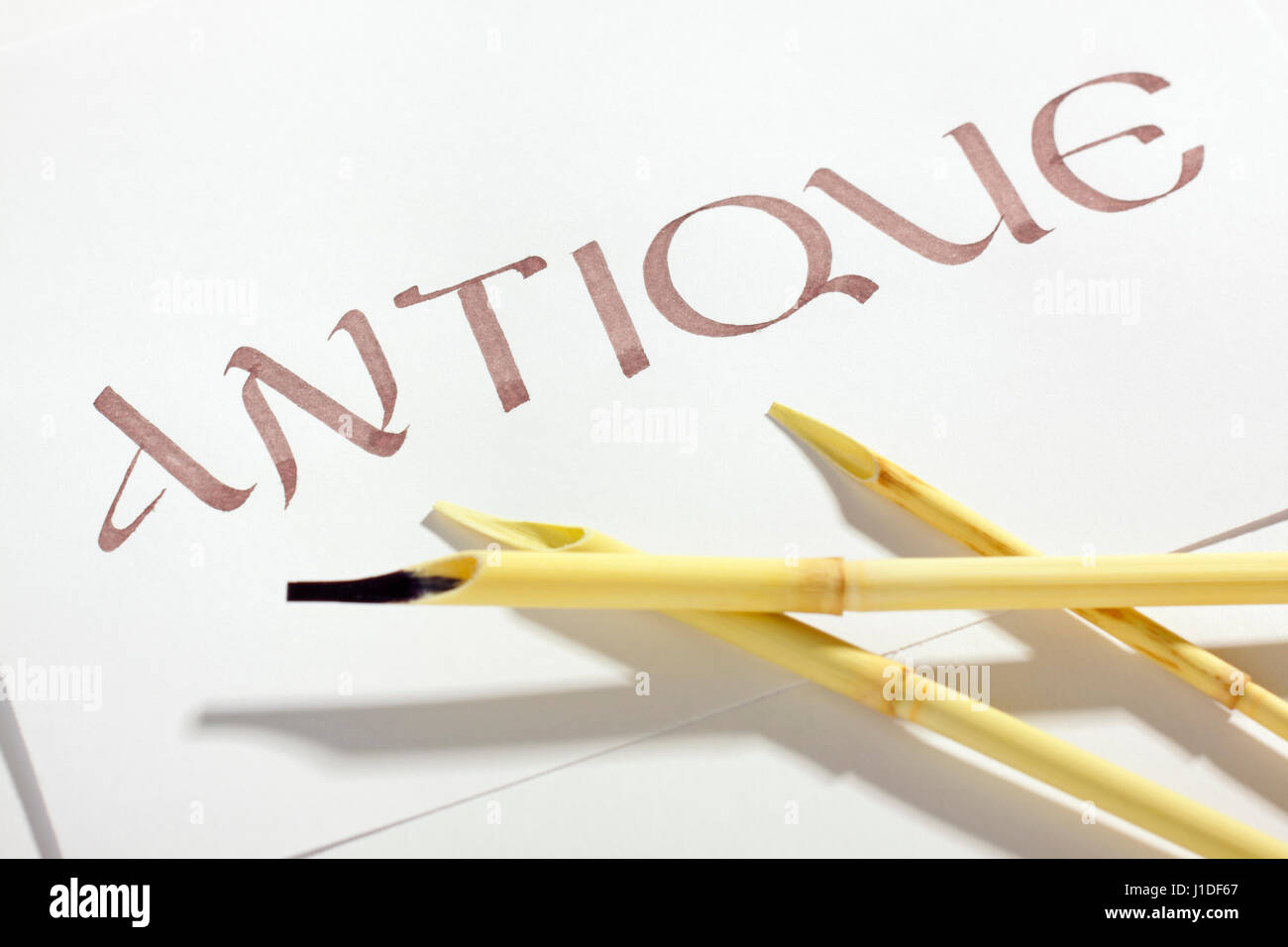 Word antique written with brown ink on the white paper sheet and three ...