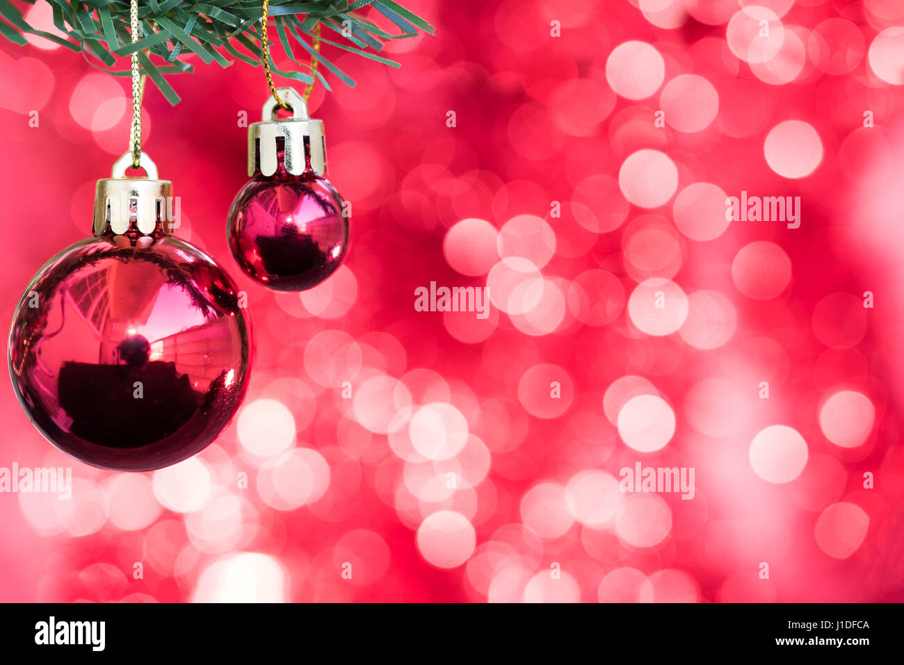 Christmas balls hanging on fir tree over red bokeh lights background ...