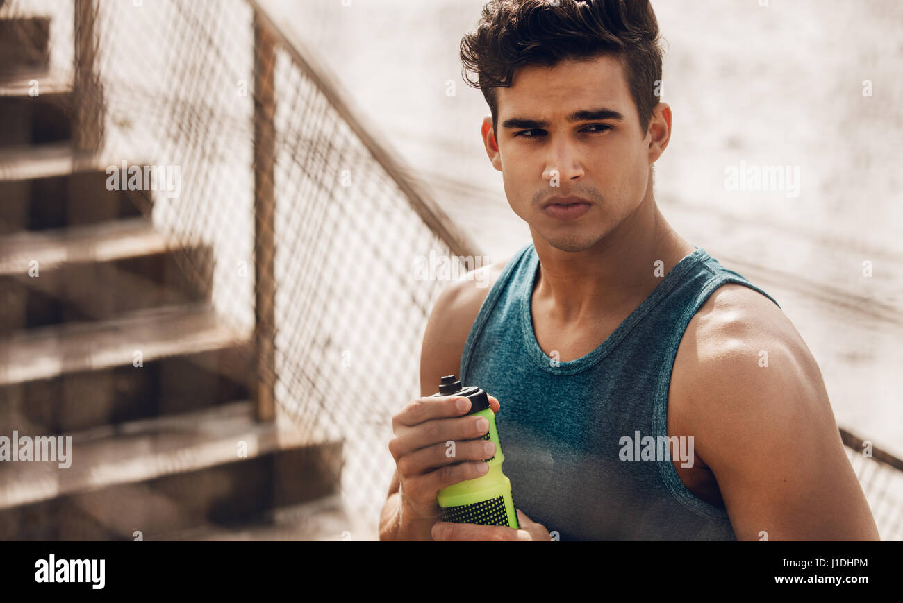 Portrait of healthy athletic man holding bottle of water. Male runner ...