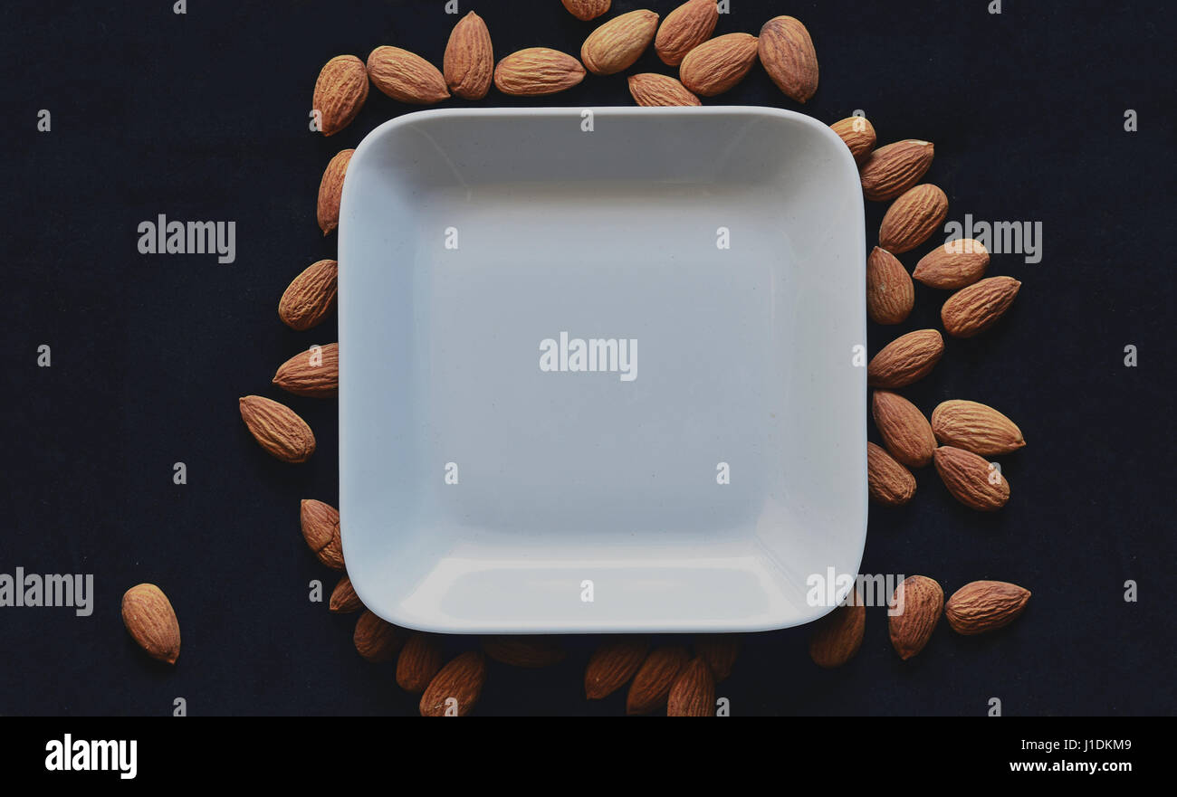 Spread Almonds outside white plate against black background Stock Photo ...