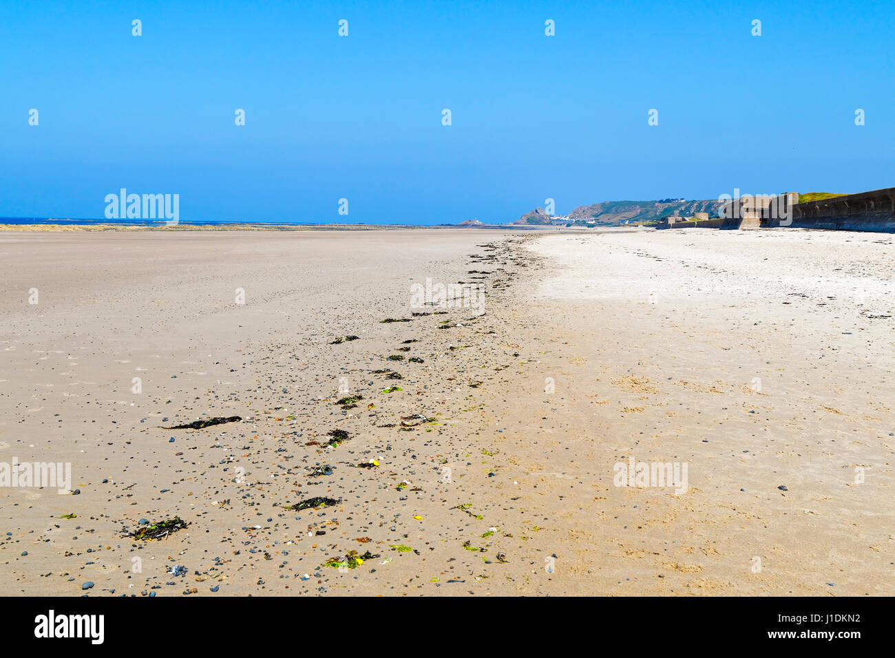 Long line of seaweed, pebbles and shells meanders along a deserted ...