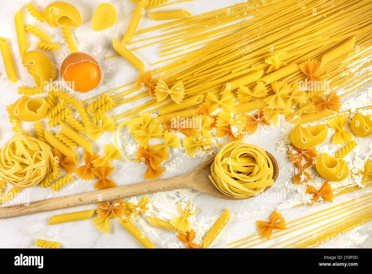 An overhead photo of various types of pasta on a white marble table ...