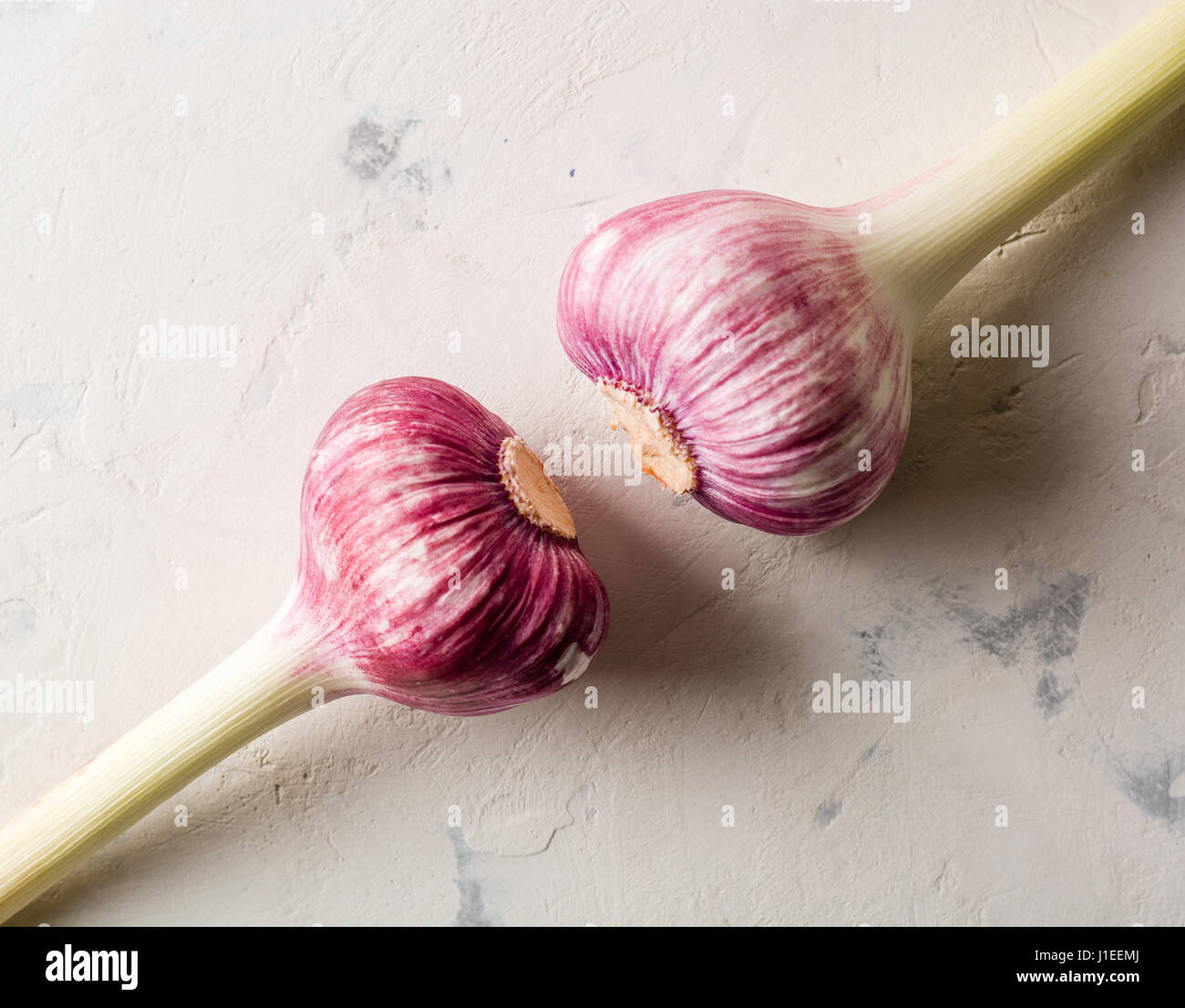 Garlic purple stalk on a white stone background. A lot of empty space ...