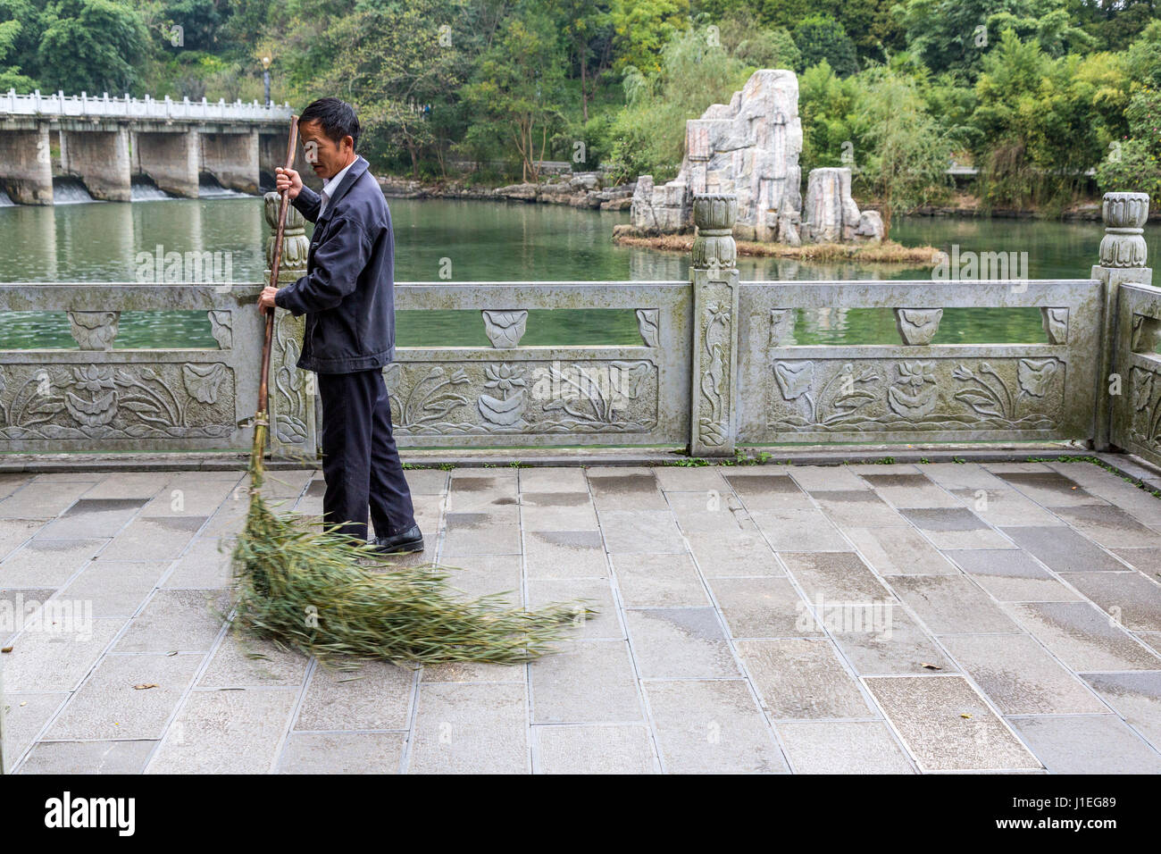 China, Guizhou, Dragon Palace Scenic Area. Man Sweeping the Terrace ...