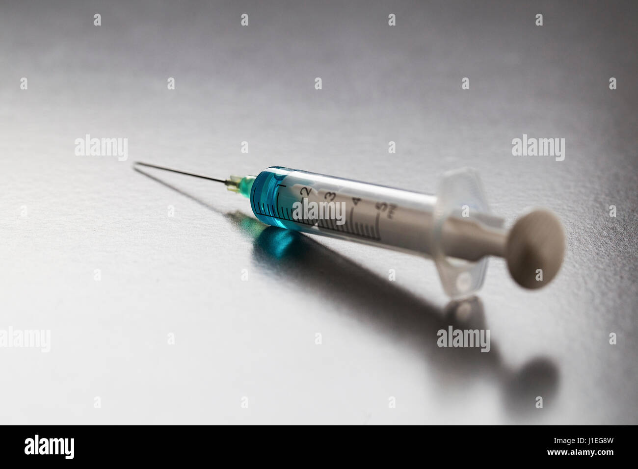 A close-up of a syringe with a blue liquid Stock Photo - Alamy