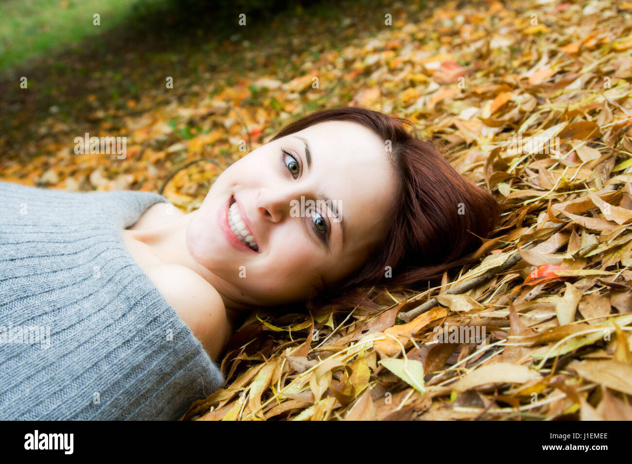 A portrait of a beautiful young caucasian girl lying down on the ground ...