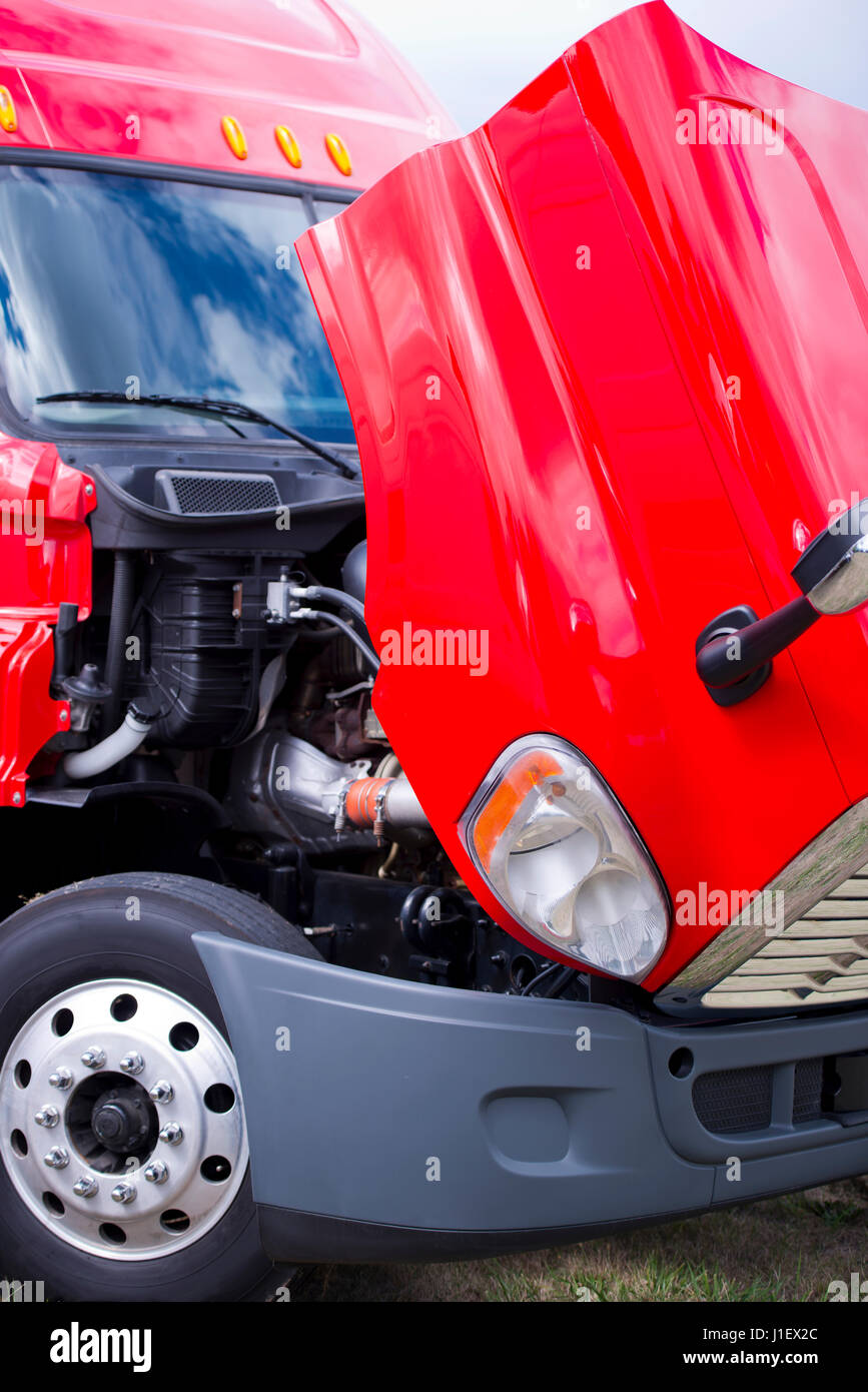 Bright modern red big rig semi-truck parked with open hood to check ...