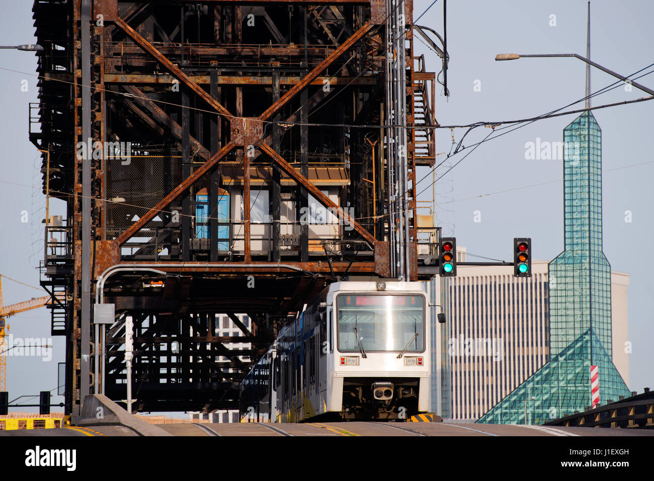 Modern streetcar on the old drawbridge with rusty farm across the river ...