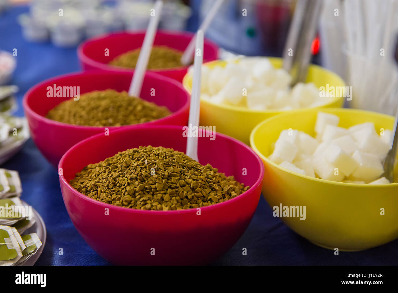 Soluble coffee in a pink plate and sugar refined in a yellow plate on a ...