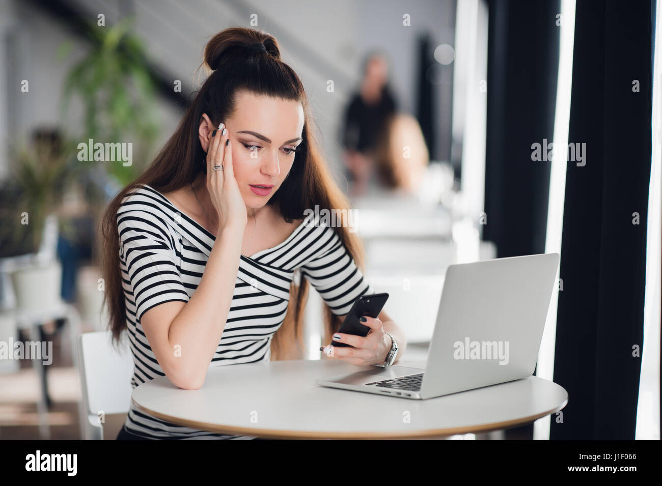 Shocked woman holding and looking sadly at mobile phone, she is ...