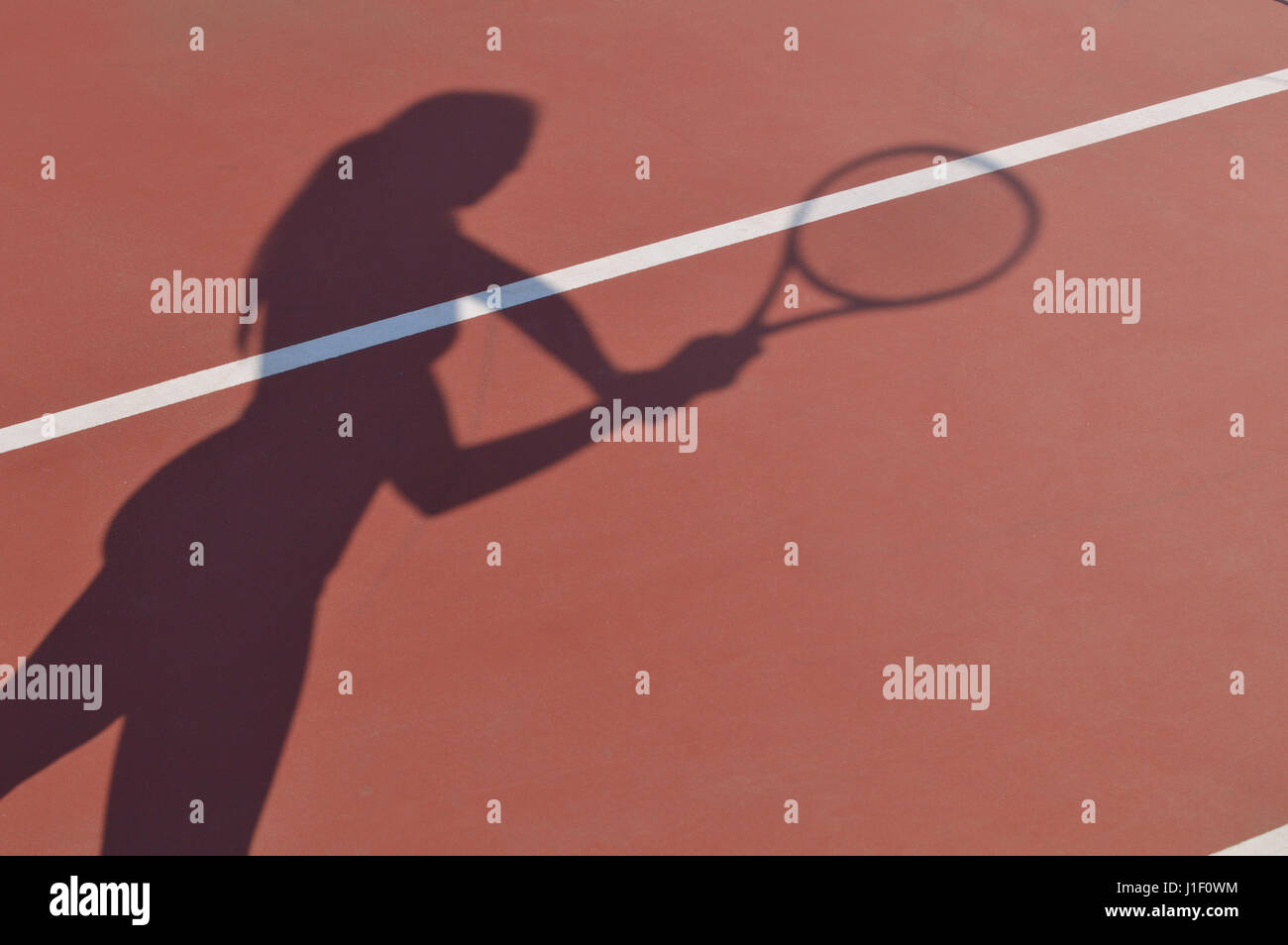 Shadow of female tennis player with racket ready to serve a tennis ball ...