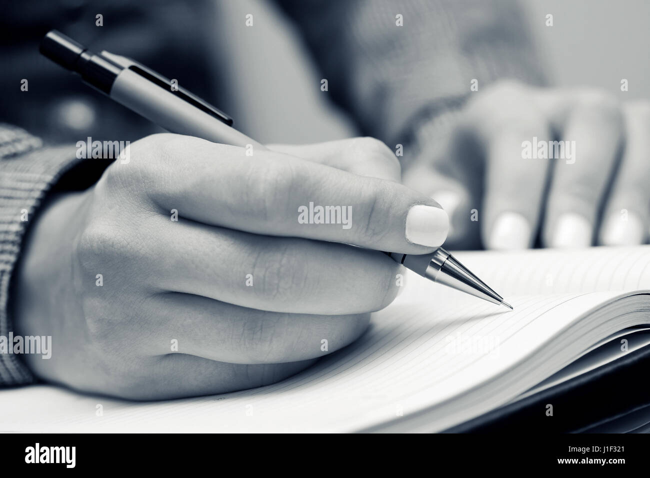 Female hand writing in notebook Stock Photo - Alamy
