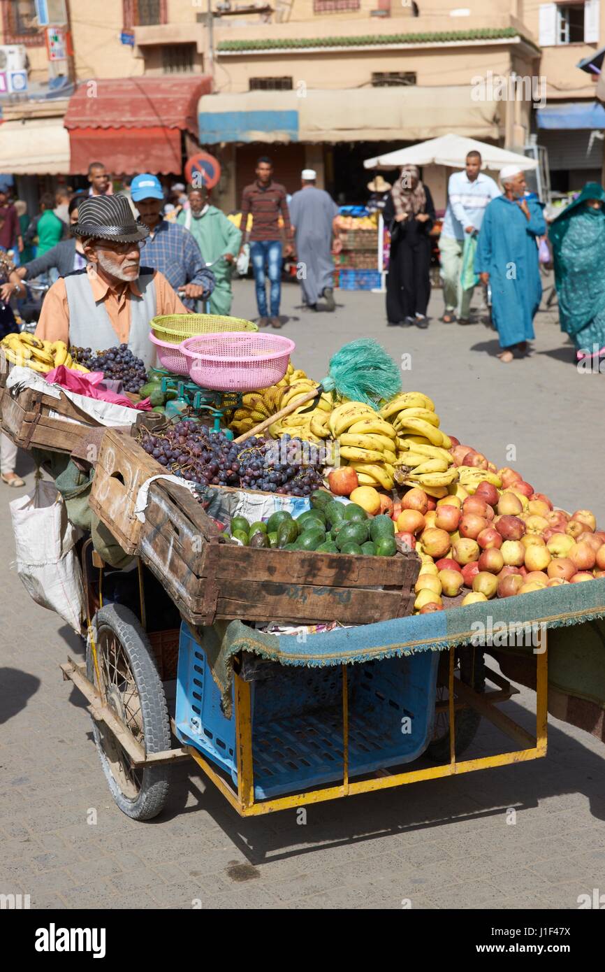 Man pushing a cart laden with fresh fruit to the market in the ancient ...