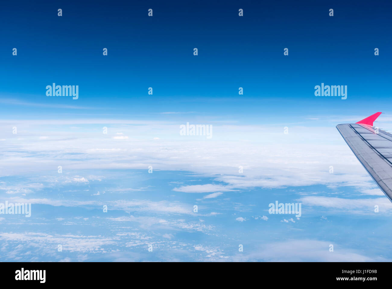 airplane wing out of window above blue sky with clouds, skyline view ...