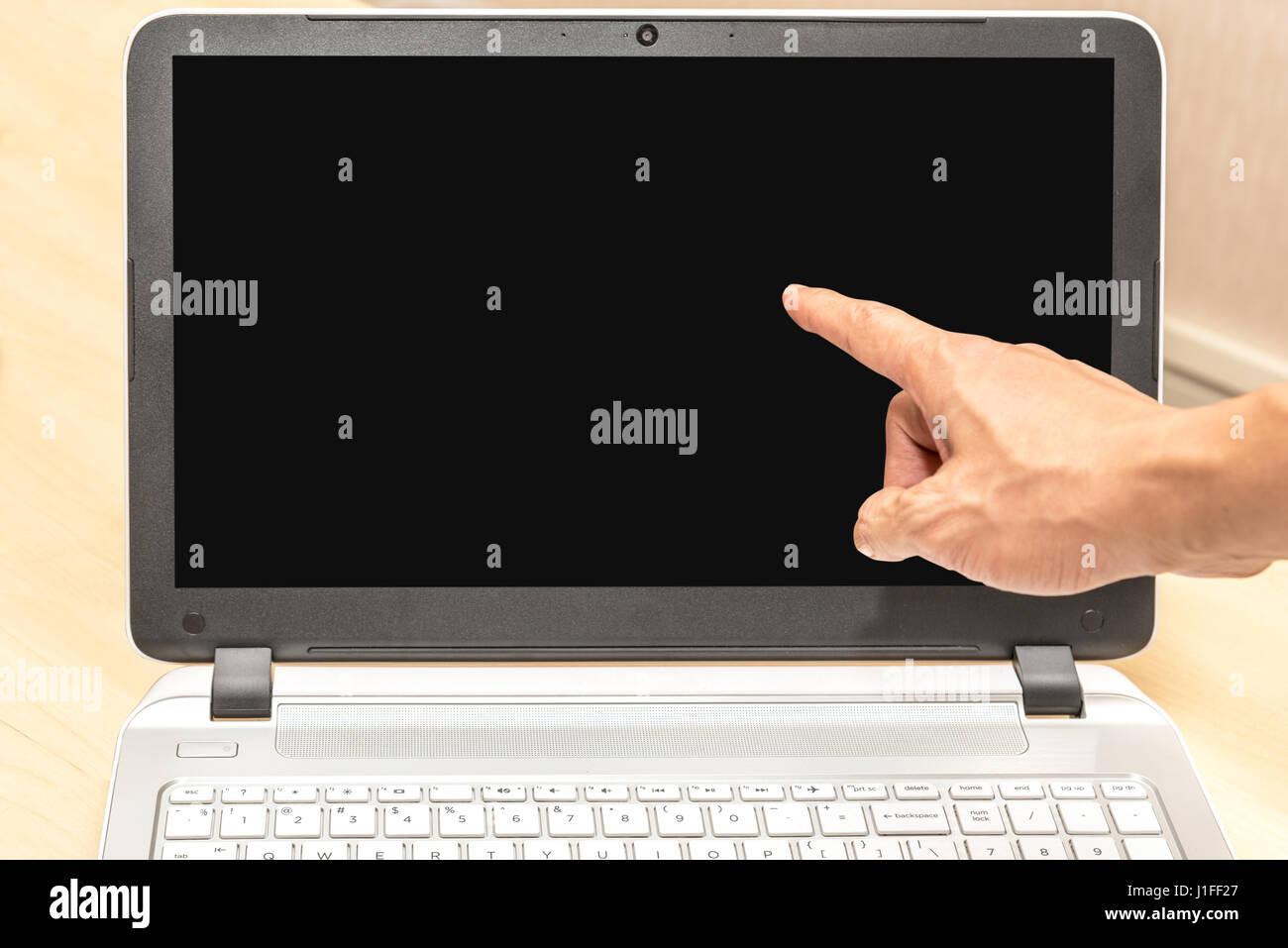 Businessman pointing finger on black laptop screen over office ...