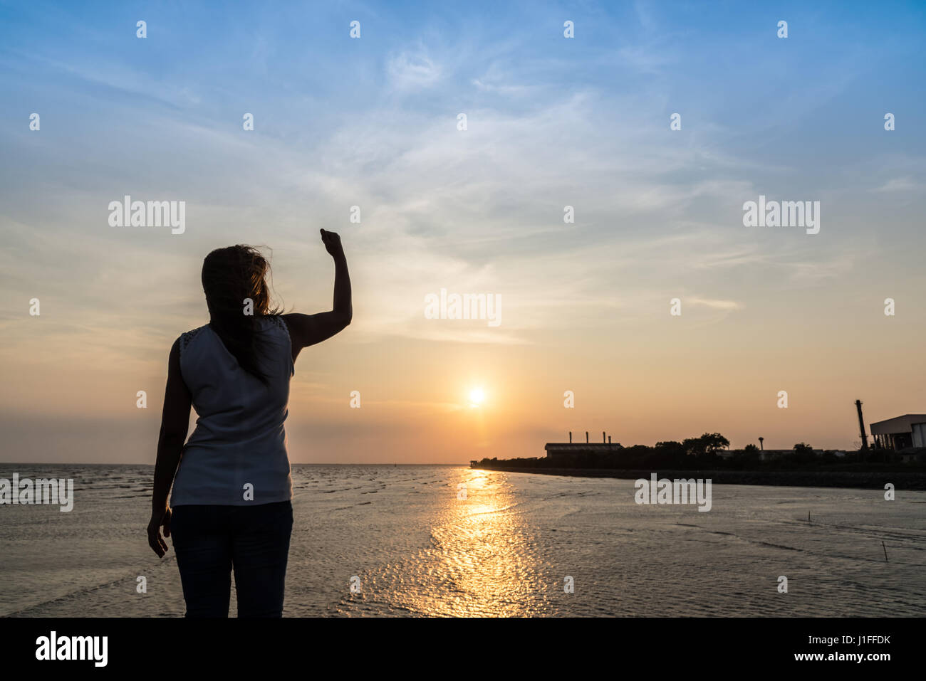 woman with arm raised up feeling success and strong on sunset ...