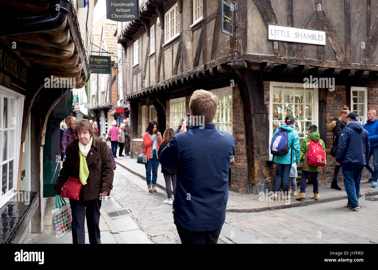 A young man using his camera phone to take photographs of The Shambles ...