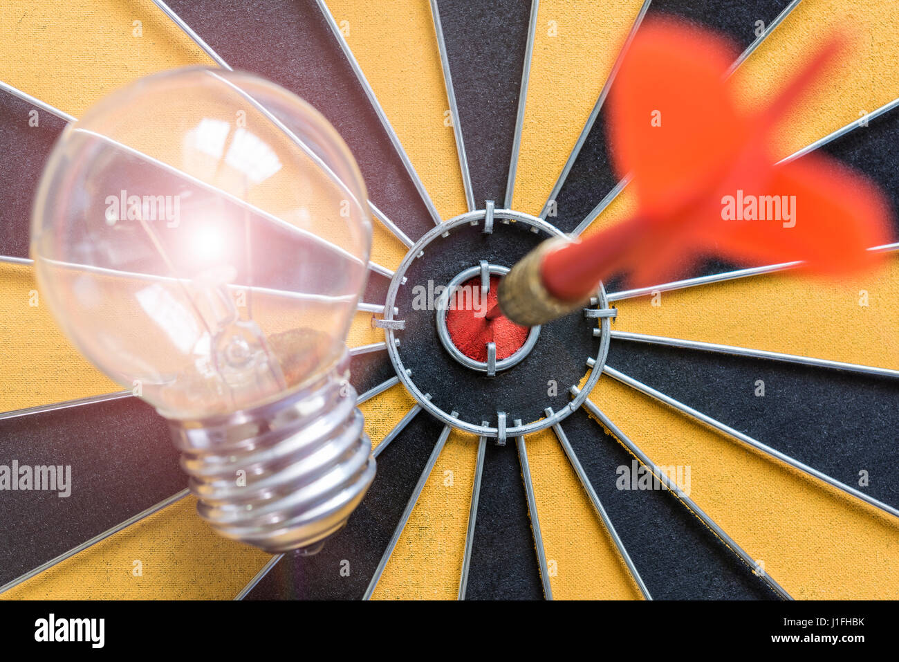 Arrow hitting the bullseye target with idea lamp on dartboard, Success ...