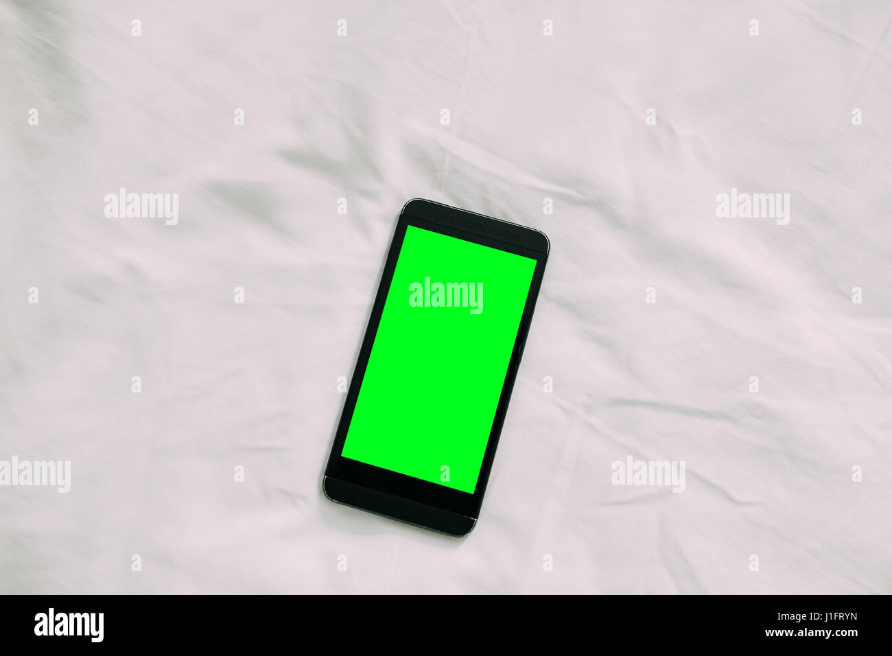 Closeup aerial view of white smart phone with green isolated screen on ...