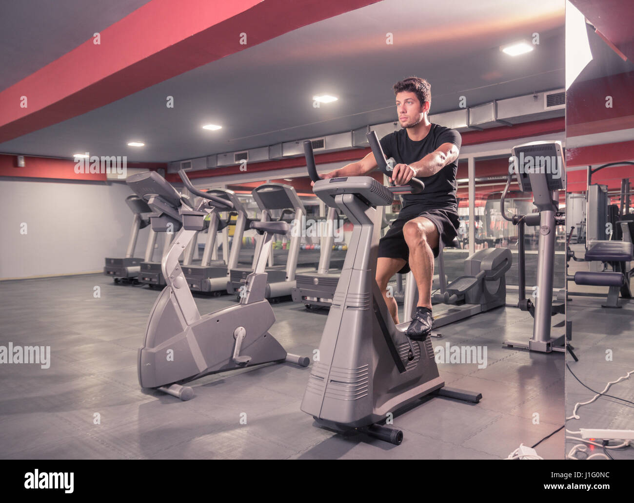 young man exercise bike, cycling, stationary exercising. Indoors gym ...