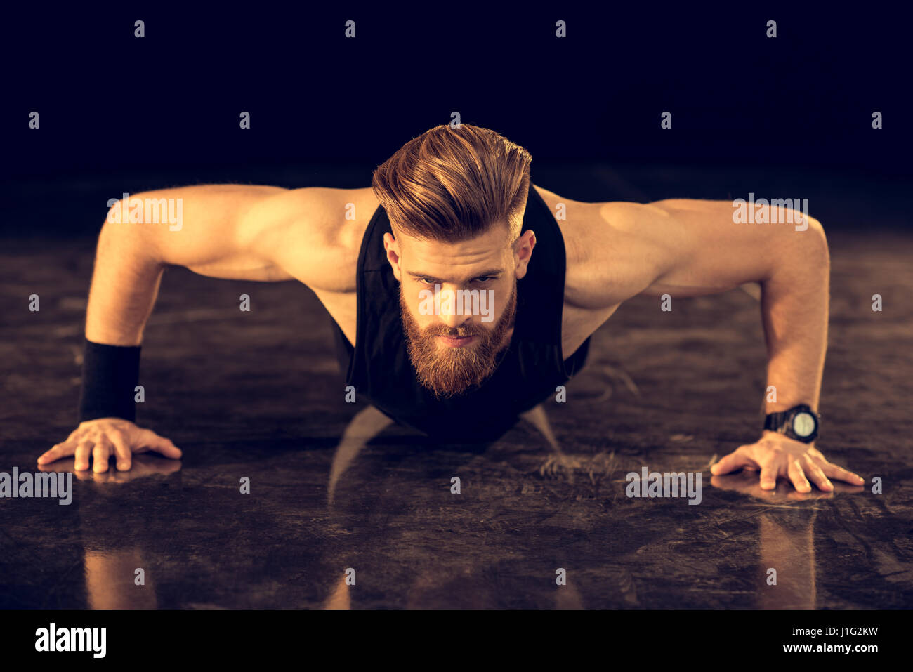 Young handsome bearded man doing push ups exercise on black Stock Photo ...