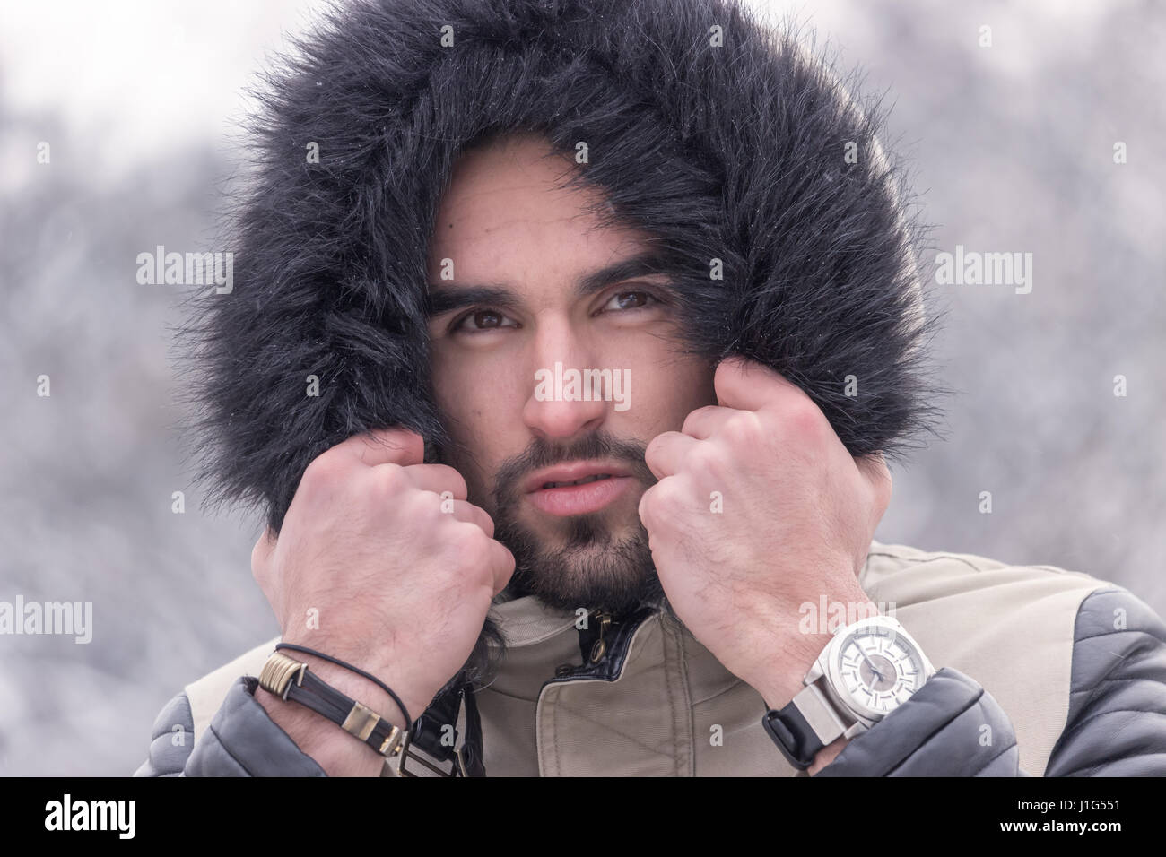 one young adult man cold winter outdoors head face closeup. looking at ...