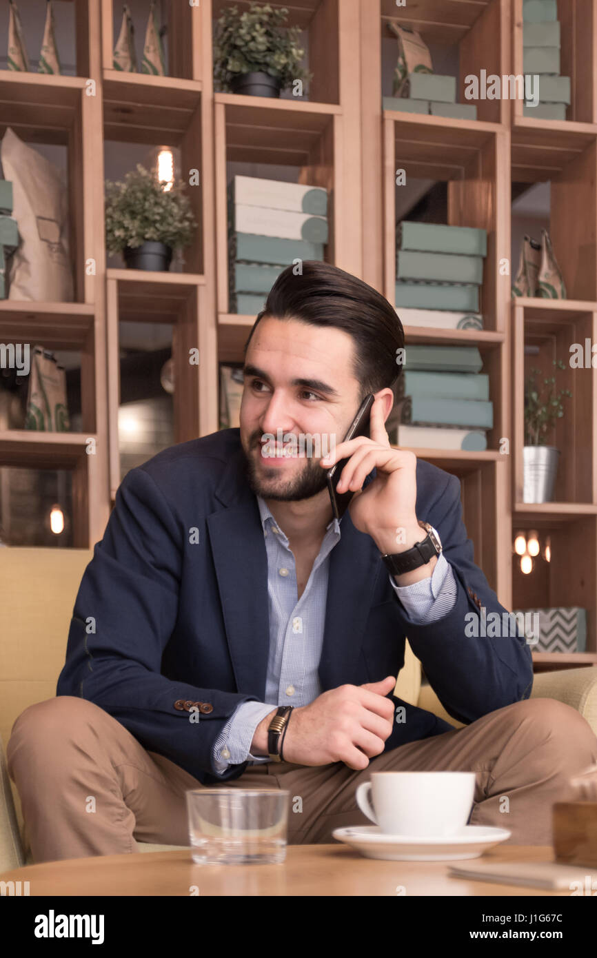 young adult smiling man, handsome, good looking, listening phone. table ...