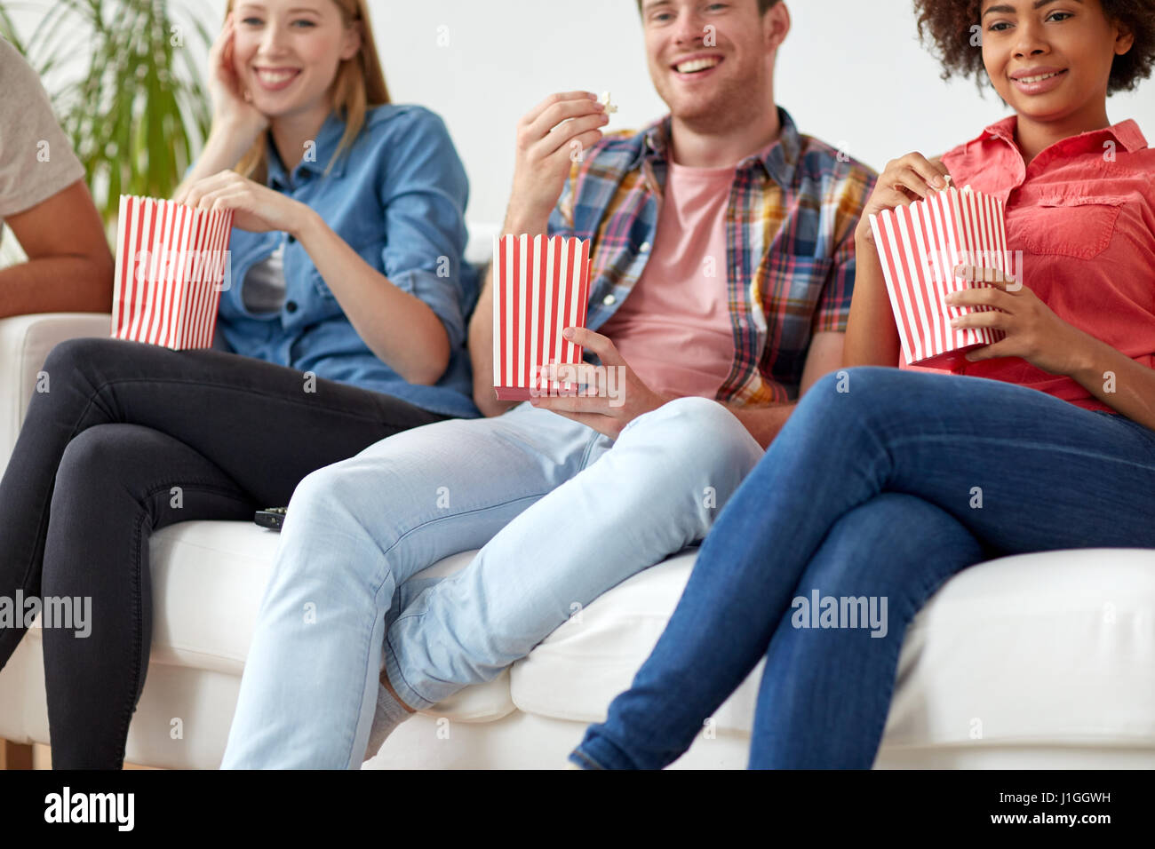 close up of happy friends eating popcorn at home Stock Photo - Alamy