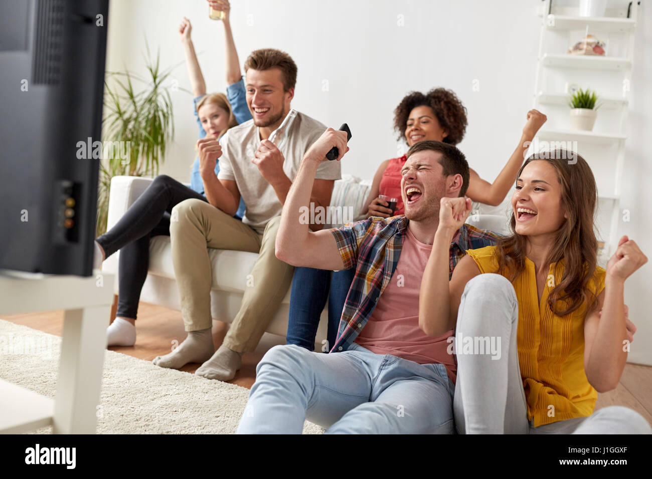 happy friends with remote watching tv at home Stock Photo - Alamy